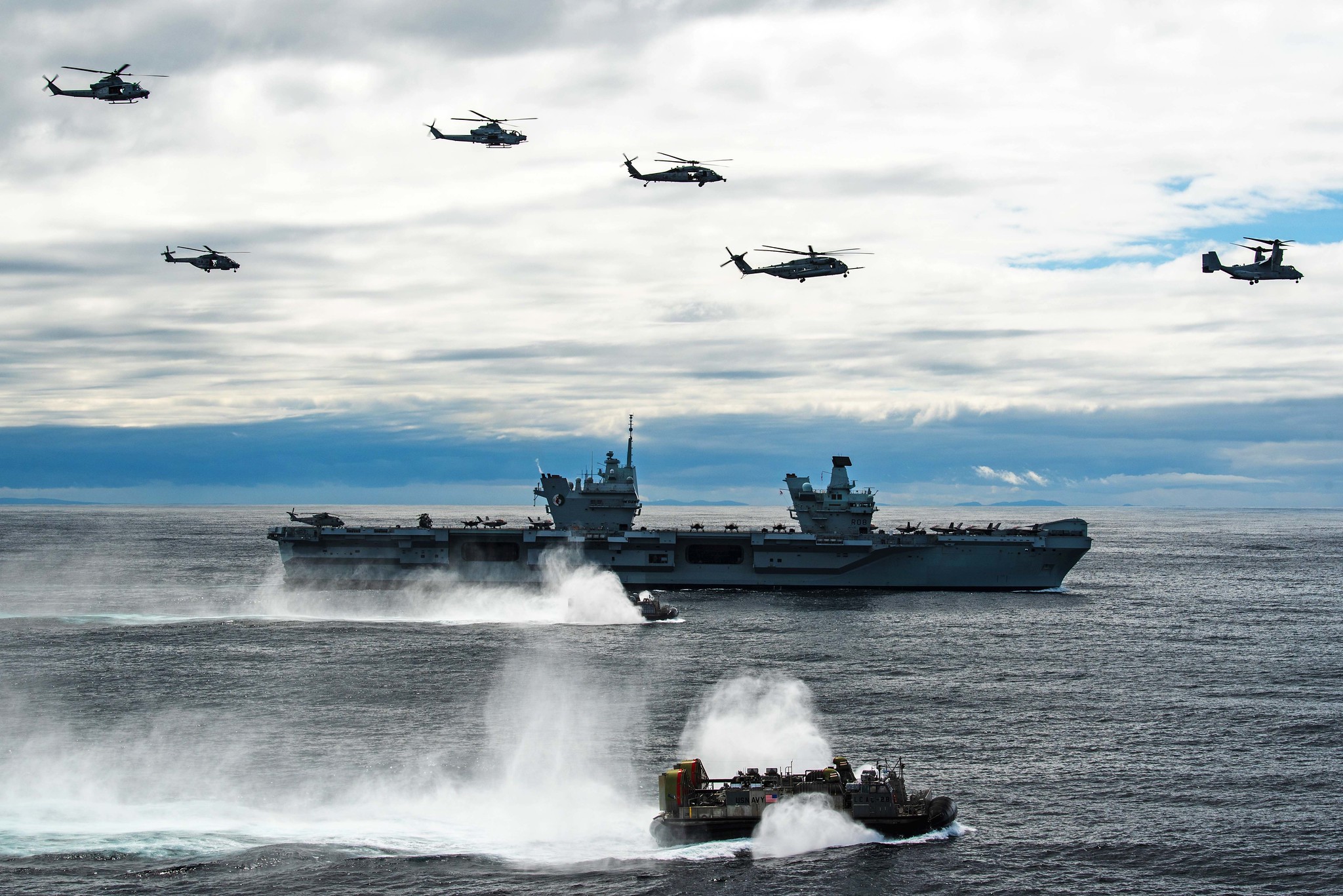 U.S. Navy aircraft fly above the Royal Navy aircraft carrier HMS Queen ...