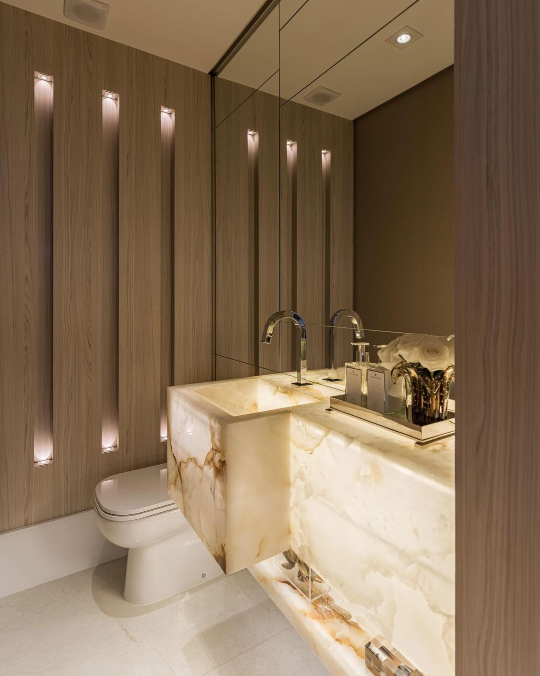 Lavabo pequeno e sofisticado com bancada em ônix iluminada e painel ...