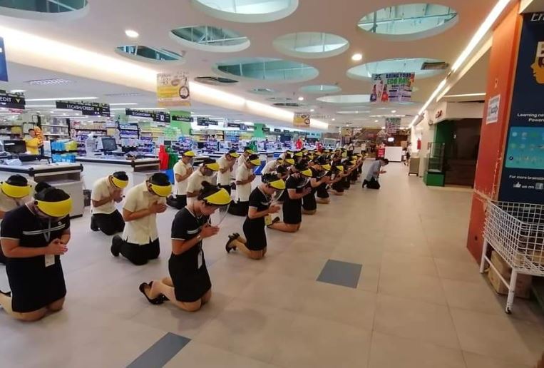Supermarket workers kneel down in prayer before work