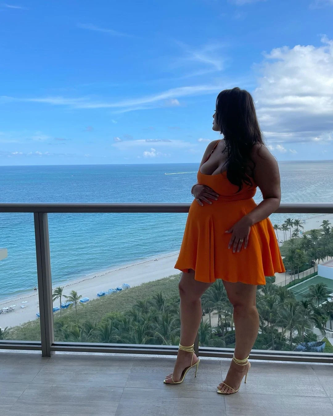 Ashley Graham flaunting her baby bump in an orange Versace maternity mini