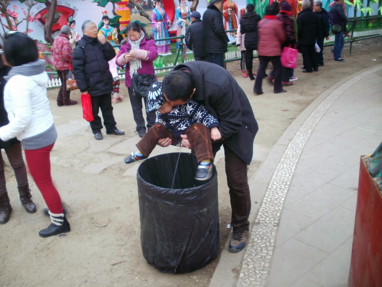 Yip! This father is holding his son over the garbage can to pee! ONLY ...